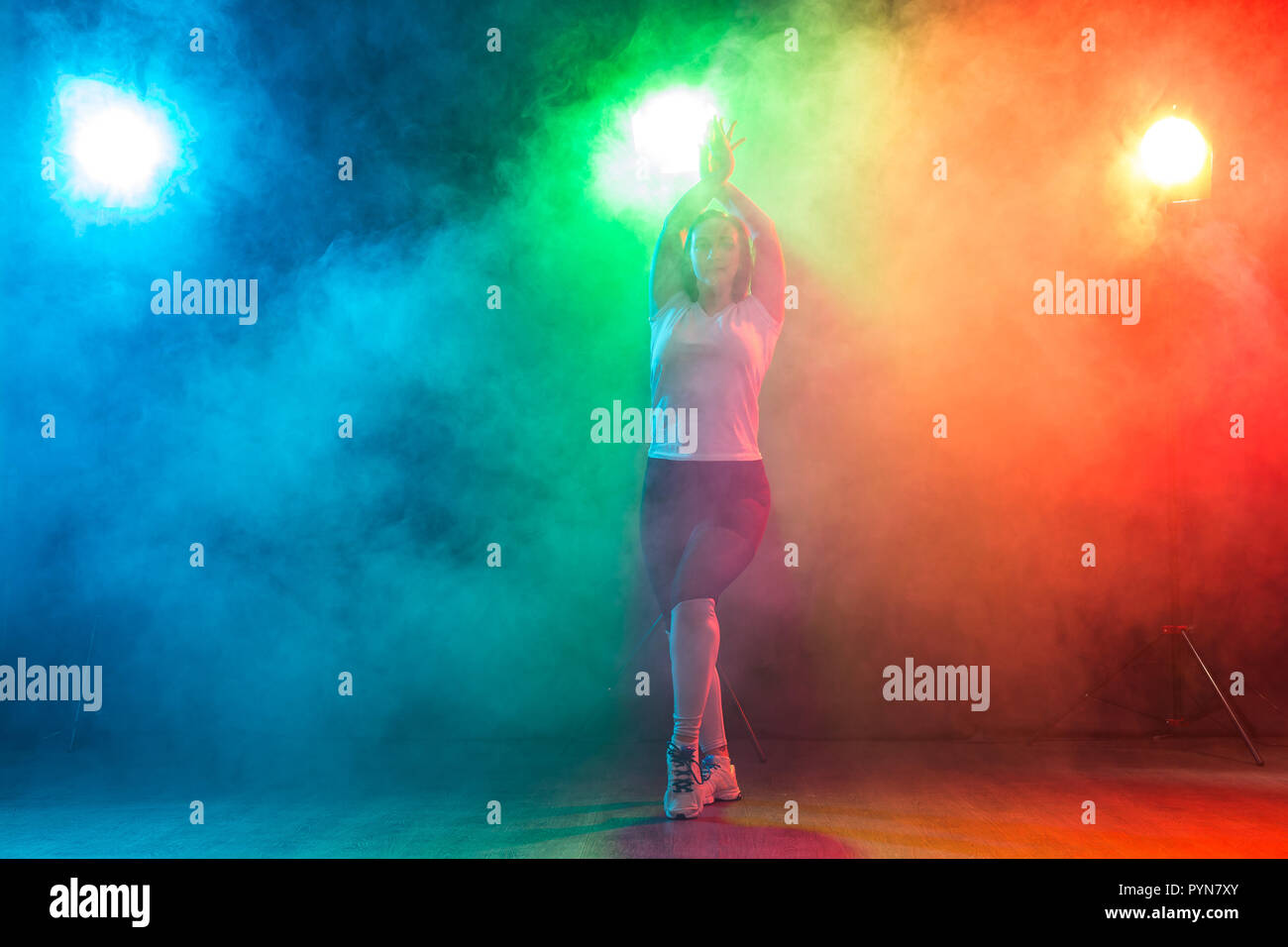 Modern dance concept - Cheerleading young woman dancing on coloured ...