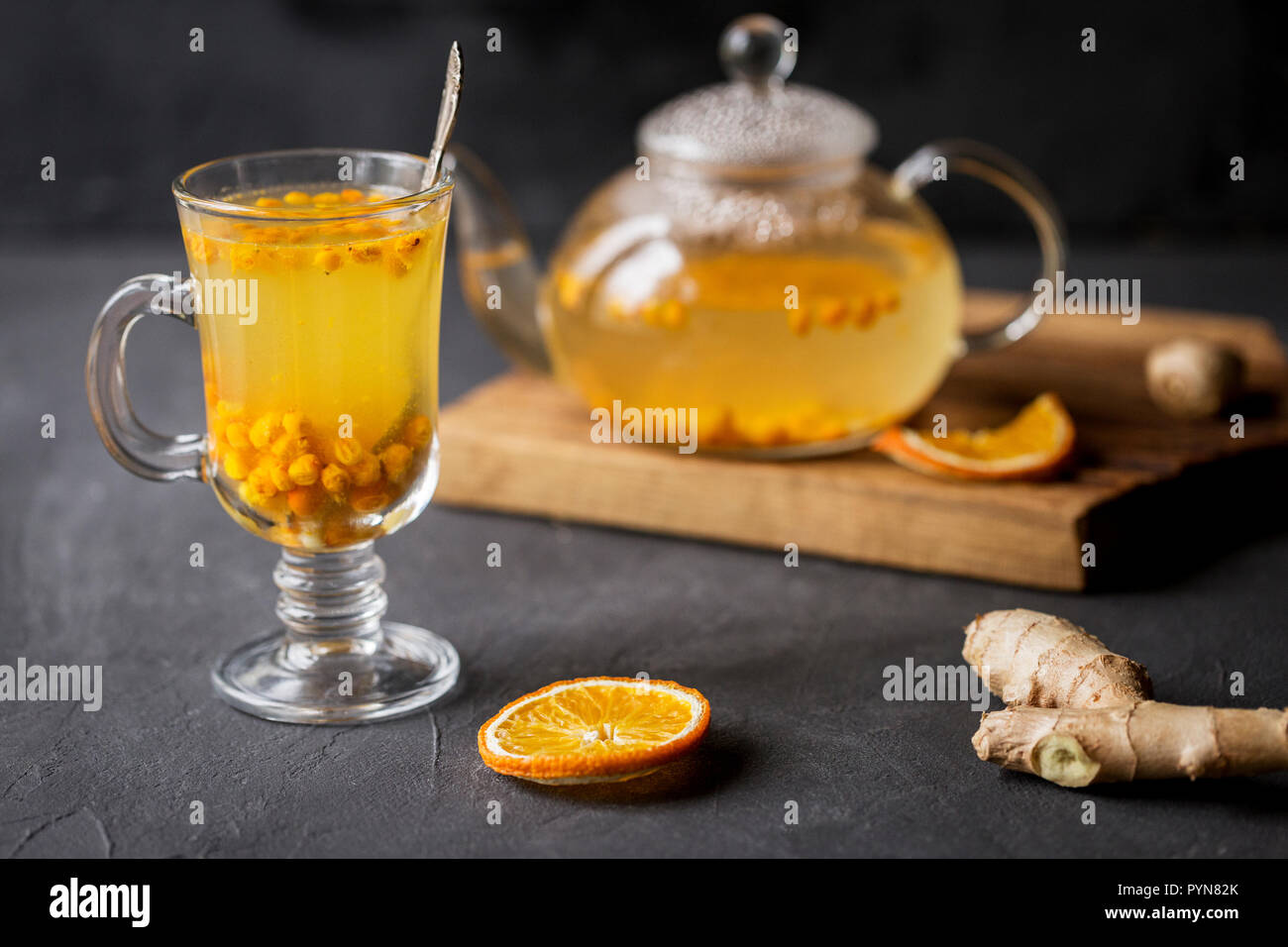 Hot sea buck thorn tea in glass teapot with glass cup and spoon, orange ...