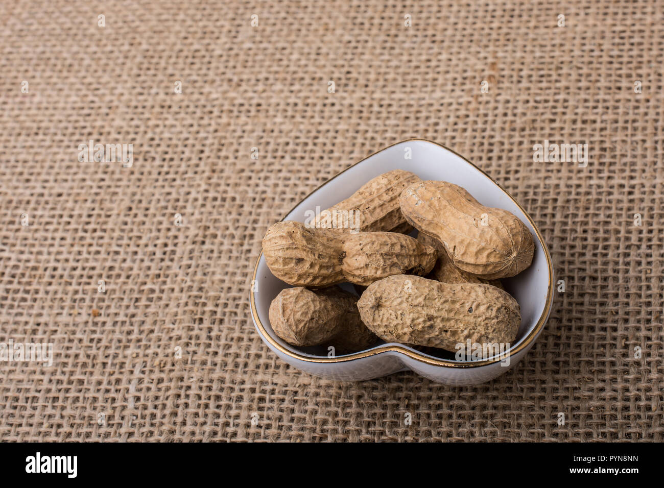 Peanuts in a heart shaped plate on canvas background Stock Photo - Alamy
