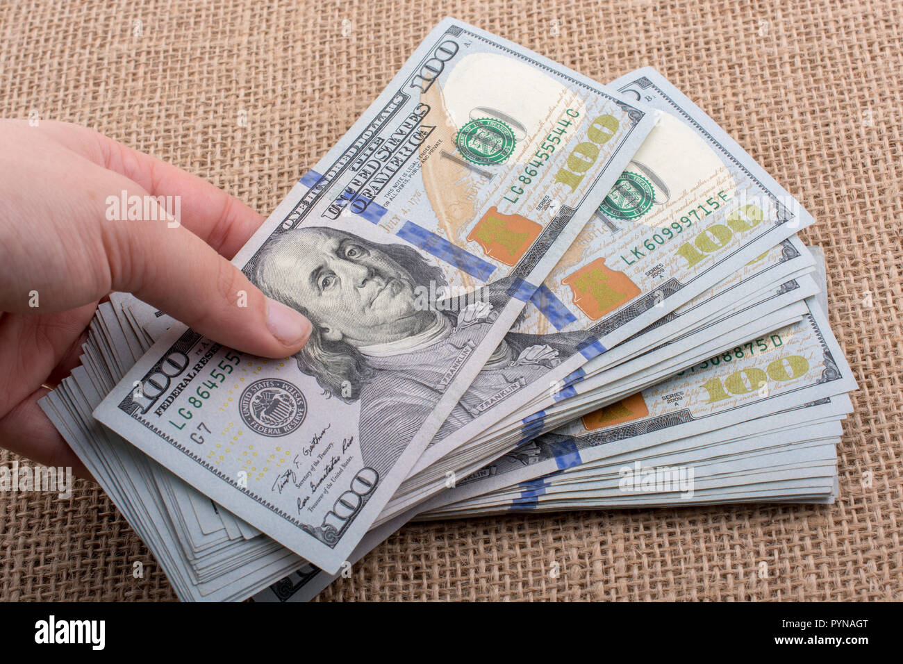 Hand holding banknote bundle of US dollar on a linen canvas background ...