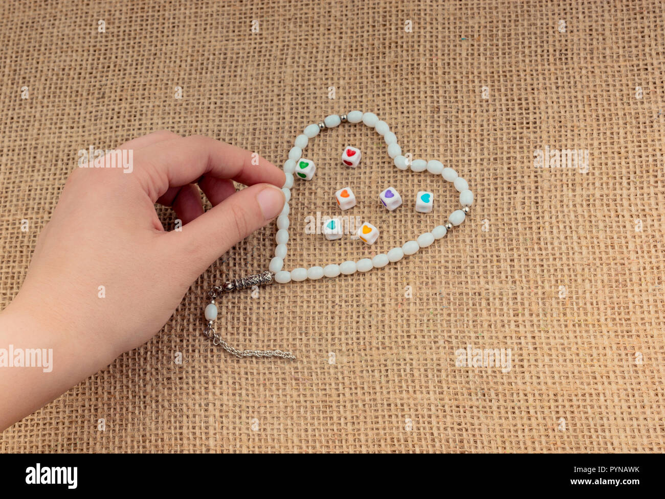 Heart shaped object in hand by a praying beads on canvas Stock Photo ...
