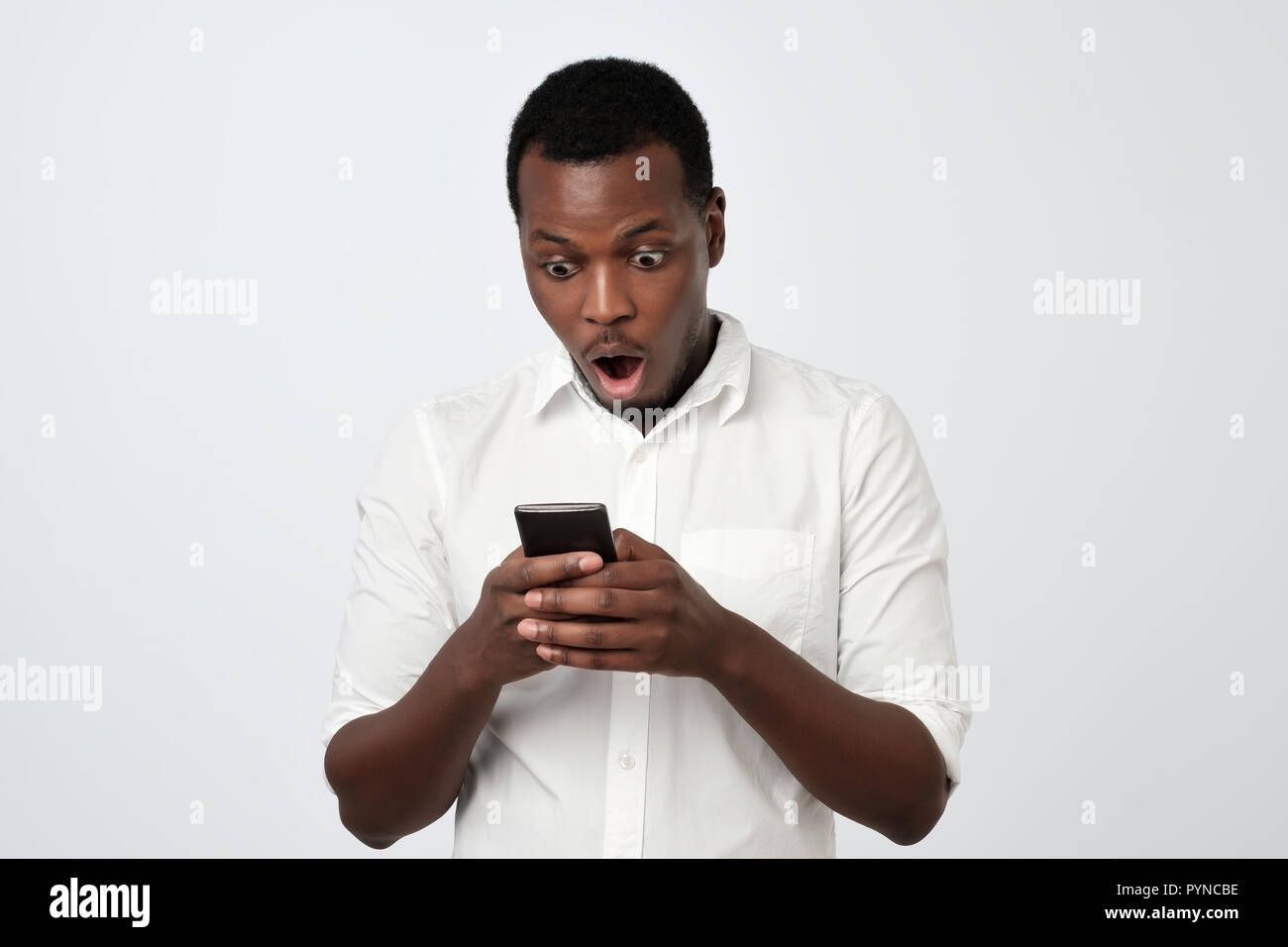 African man looking at phone seeing shocking news or photos with ...