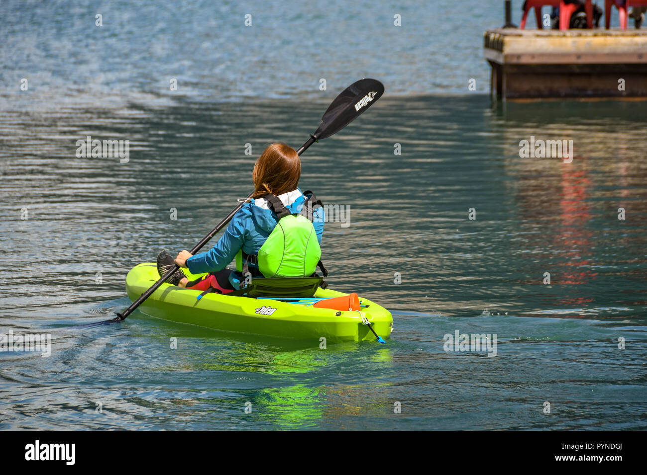 BANFF, AB, CANADA - JUNE 2018: Visitor paddling a small plastic kayak ...