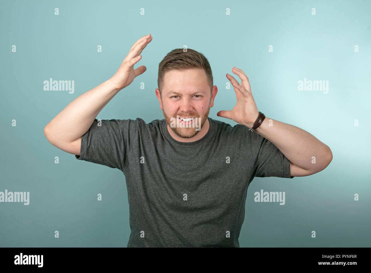 Frustrated angry man snarling and gesturing with his hands either side ...