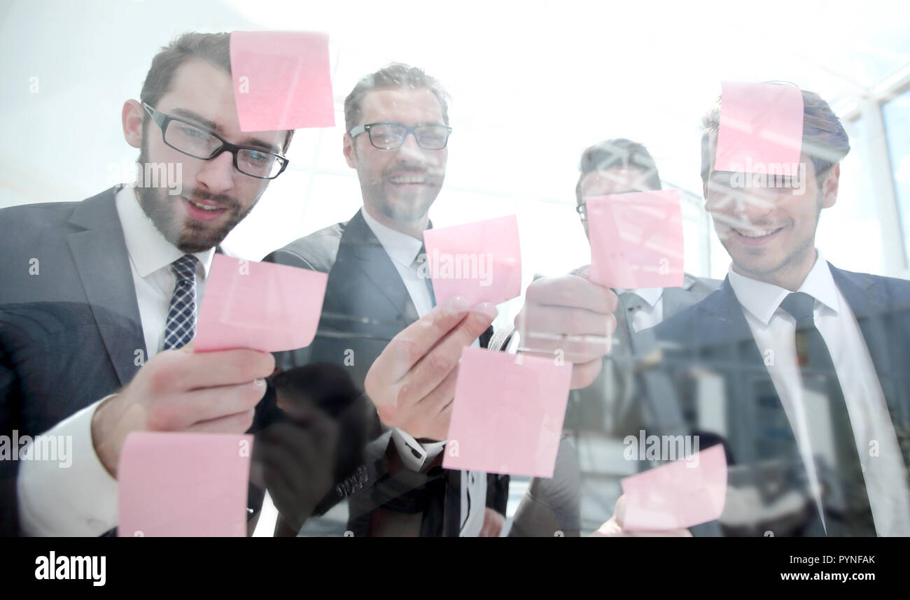 close up.successful employees reading sticky notes on glas Stock Photo ...