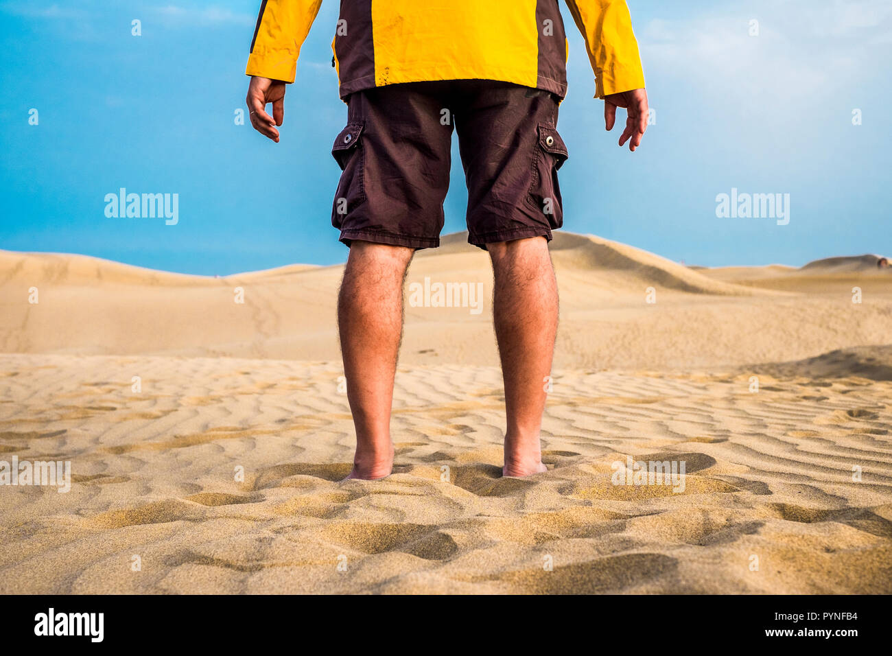 lonely man standing with the dunes yellow desert in front of him ...