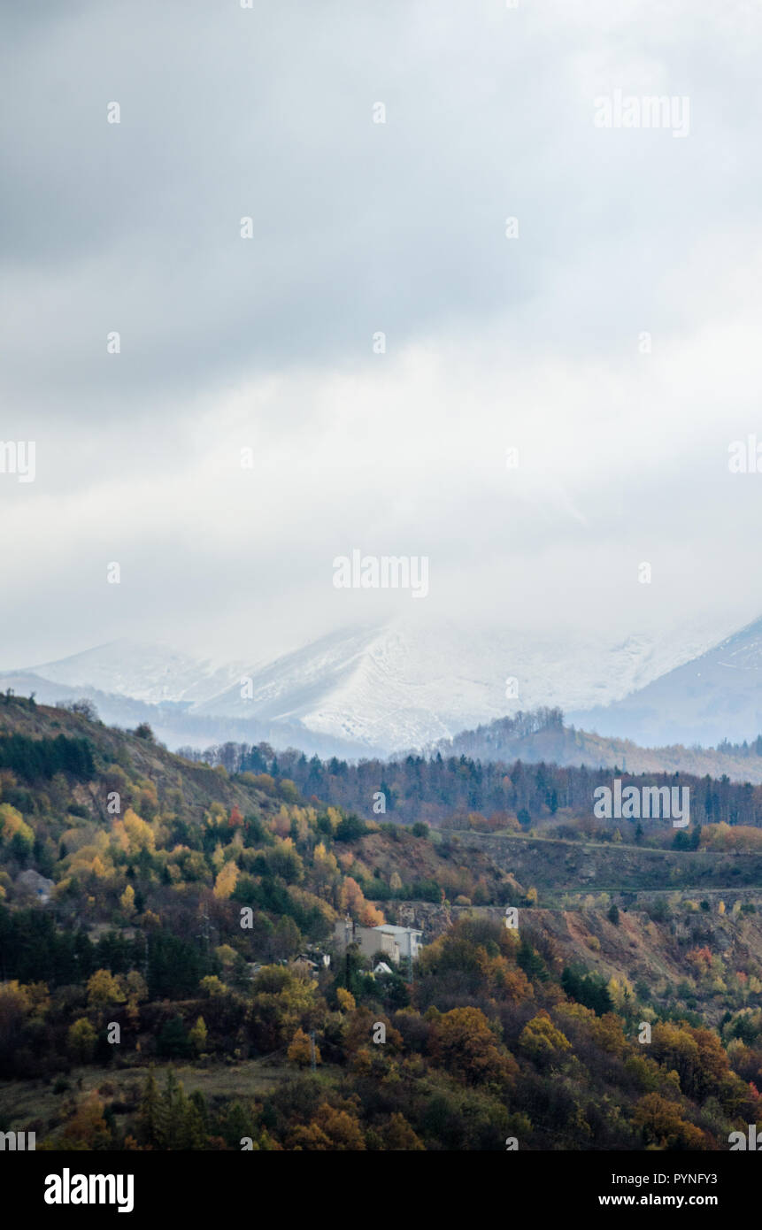 Contrast between autumn hills and snow covered high mountains Stock ...