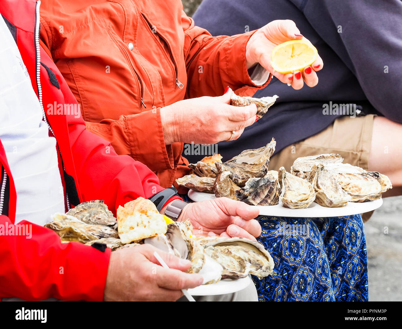 Man and woman couple eating oysters on white plate lunch time outdoor ...