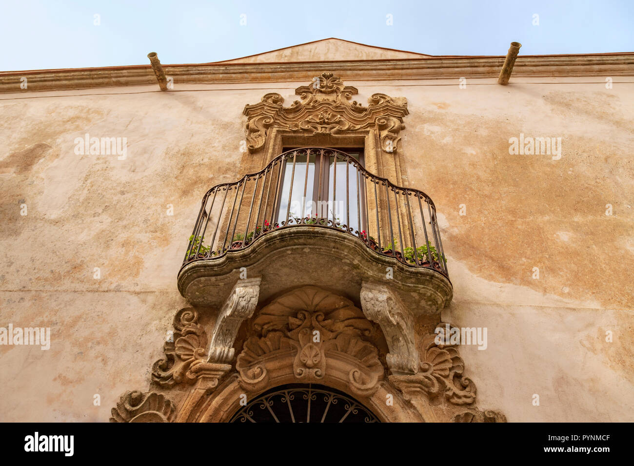 Facade of a house with a wrought-iron balcony and ornate, stucco ...