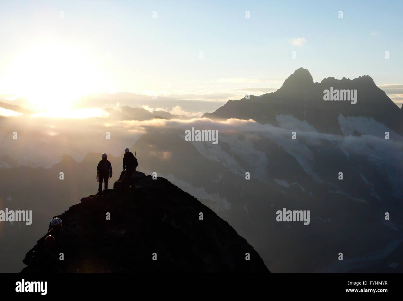 mountain climbers on a rocky ridge at sunrise climbing Eiger mountain ...