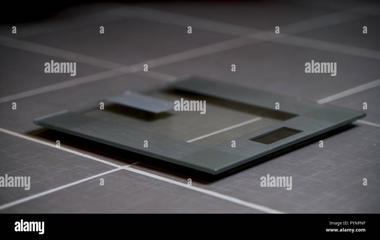 Glass modern design digital weight scales in bathroom on tiled floor ...