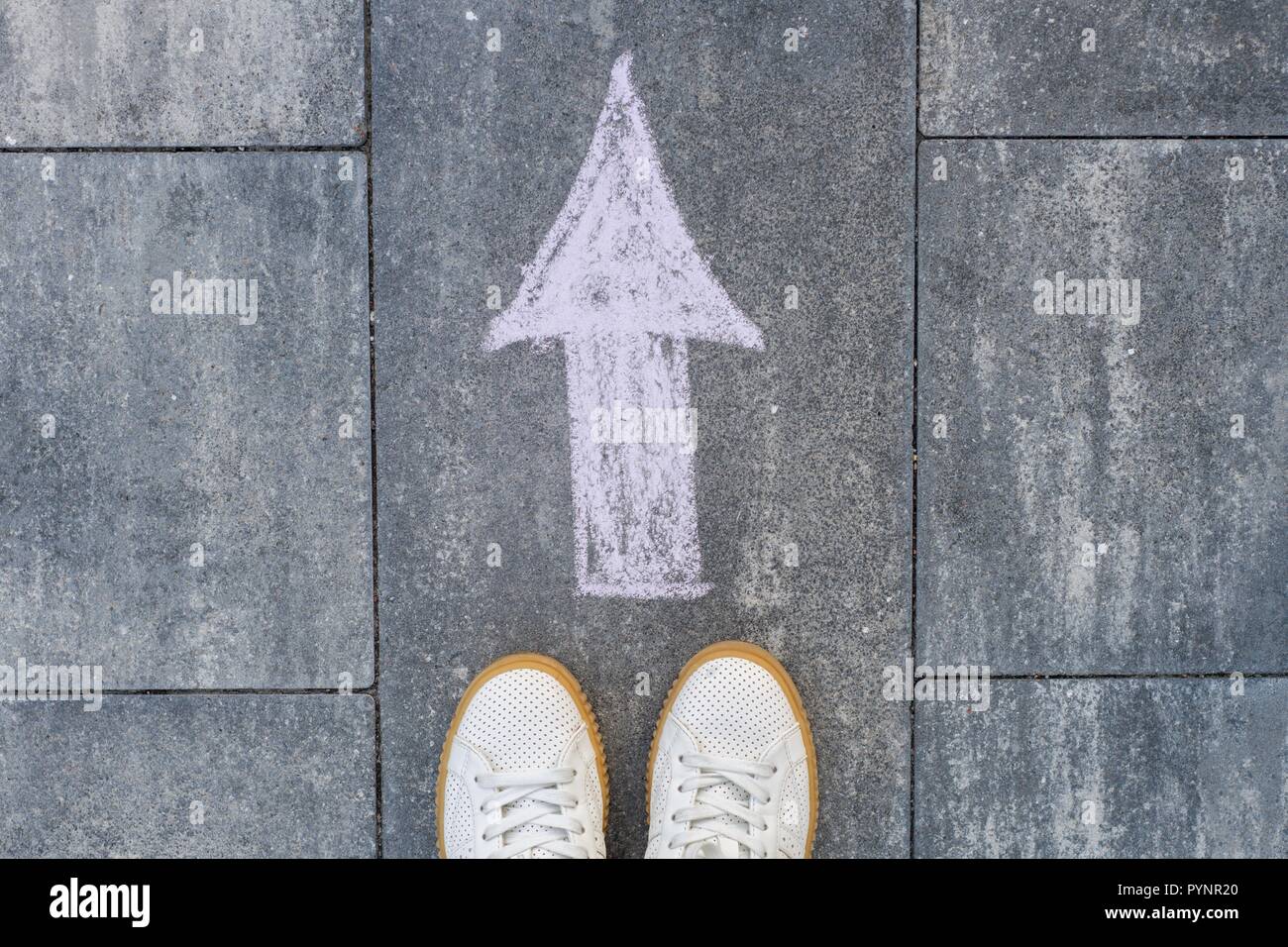 Feet and arrow on road Stock Photo - Alamy