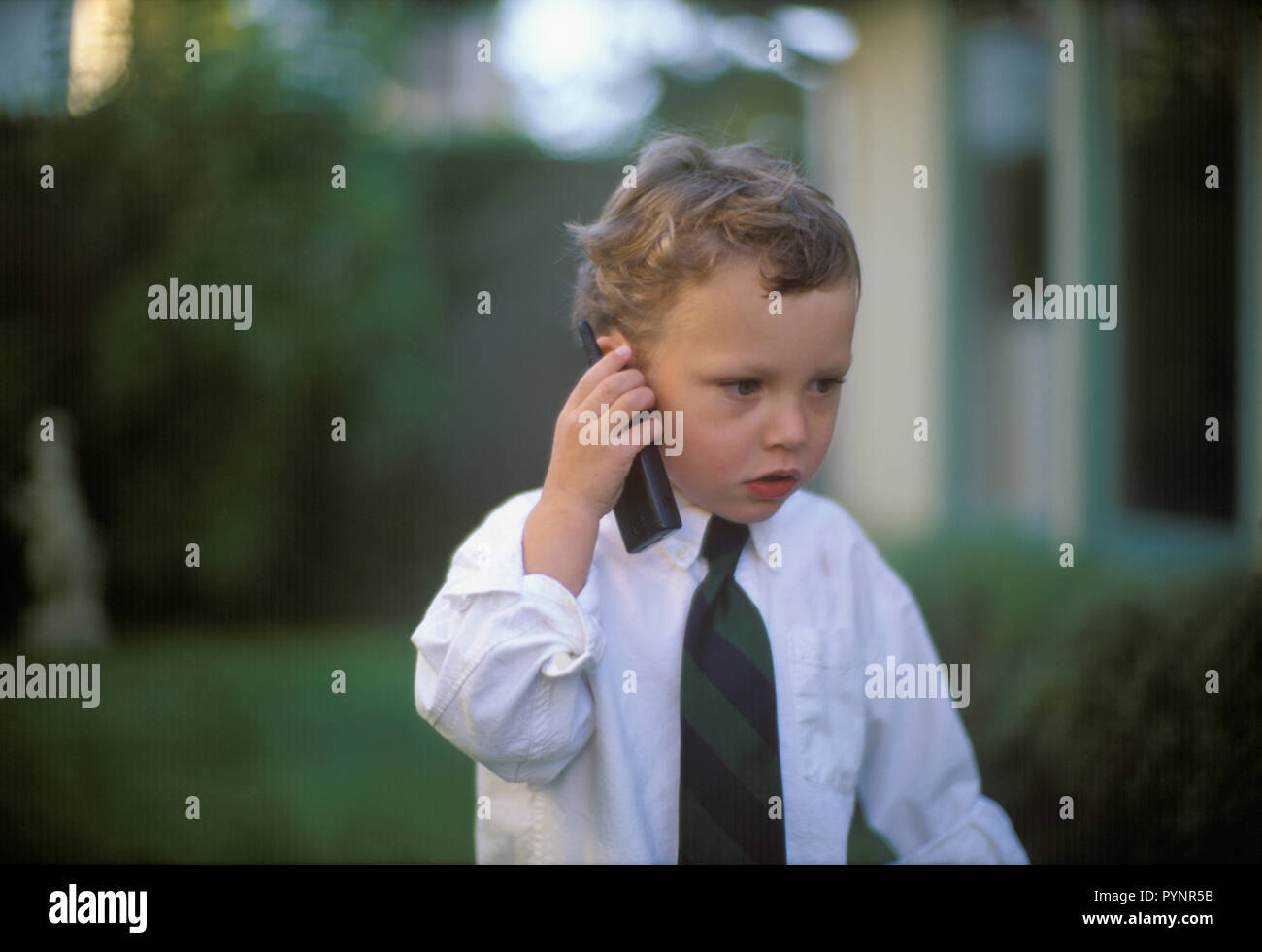 A formally dressed little boy speaking on a cell phone Stock Photo - Alamy