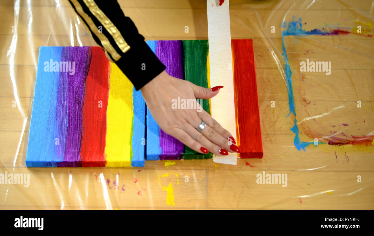 Female artist painting a rainbow with acrylic colors on canvas, hoe ...