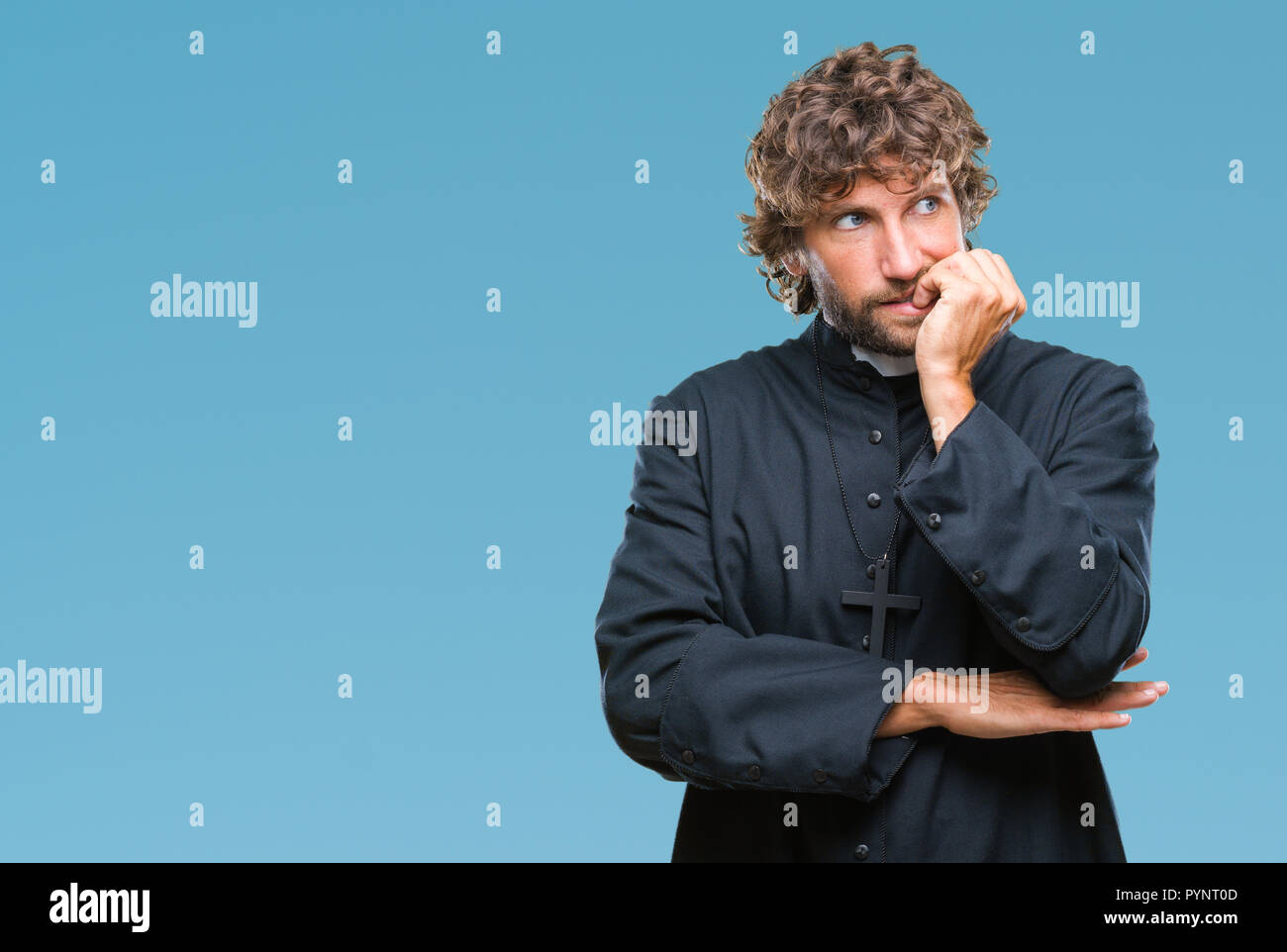 Handsome hispanic catholic priest man over isolated background looking ...