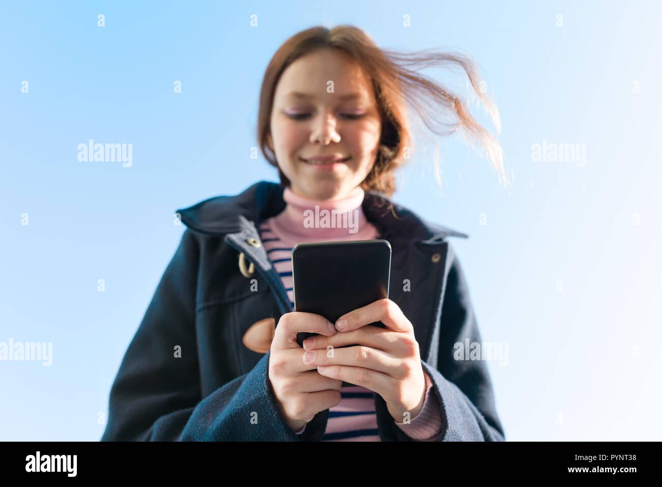 Young girl with mobile phone, background blue sky Stock Photo - Alamy