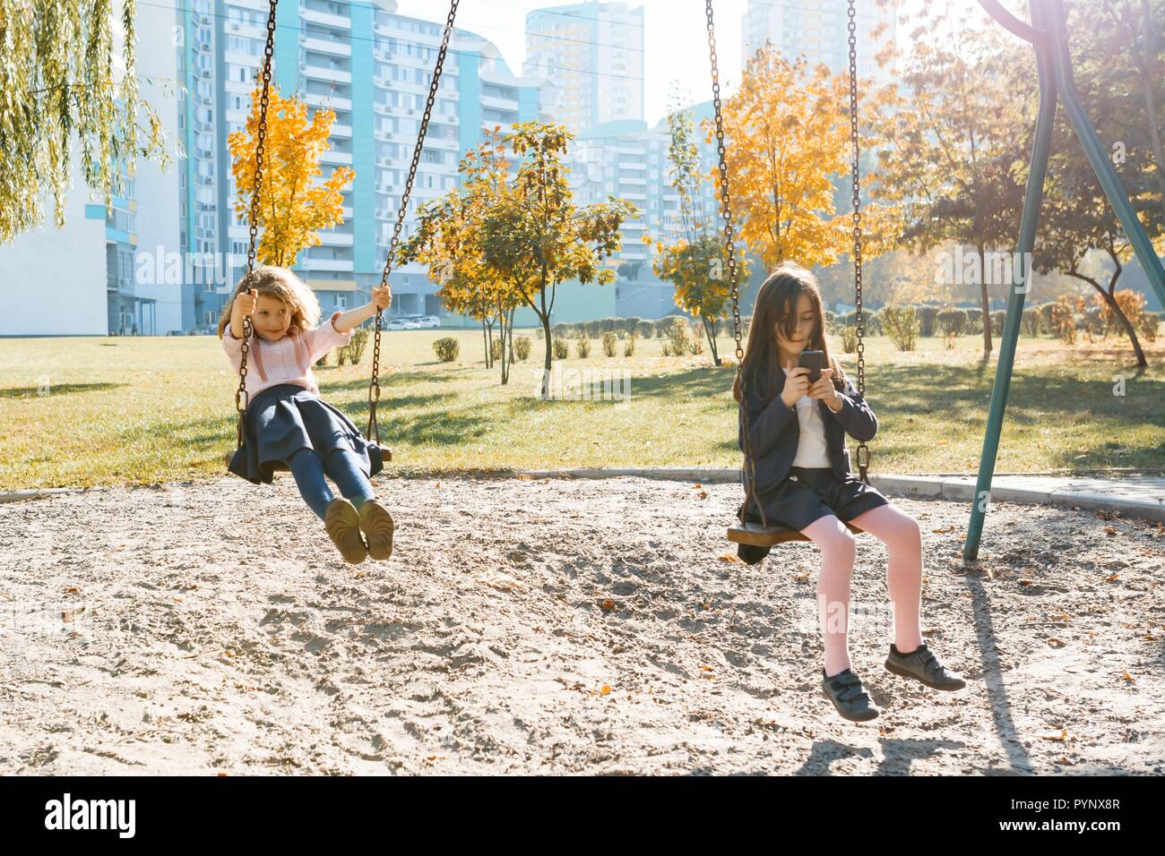 Children ride on a swing in autumn park Stock Photo - Alamy