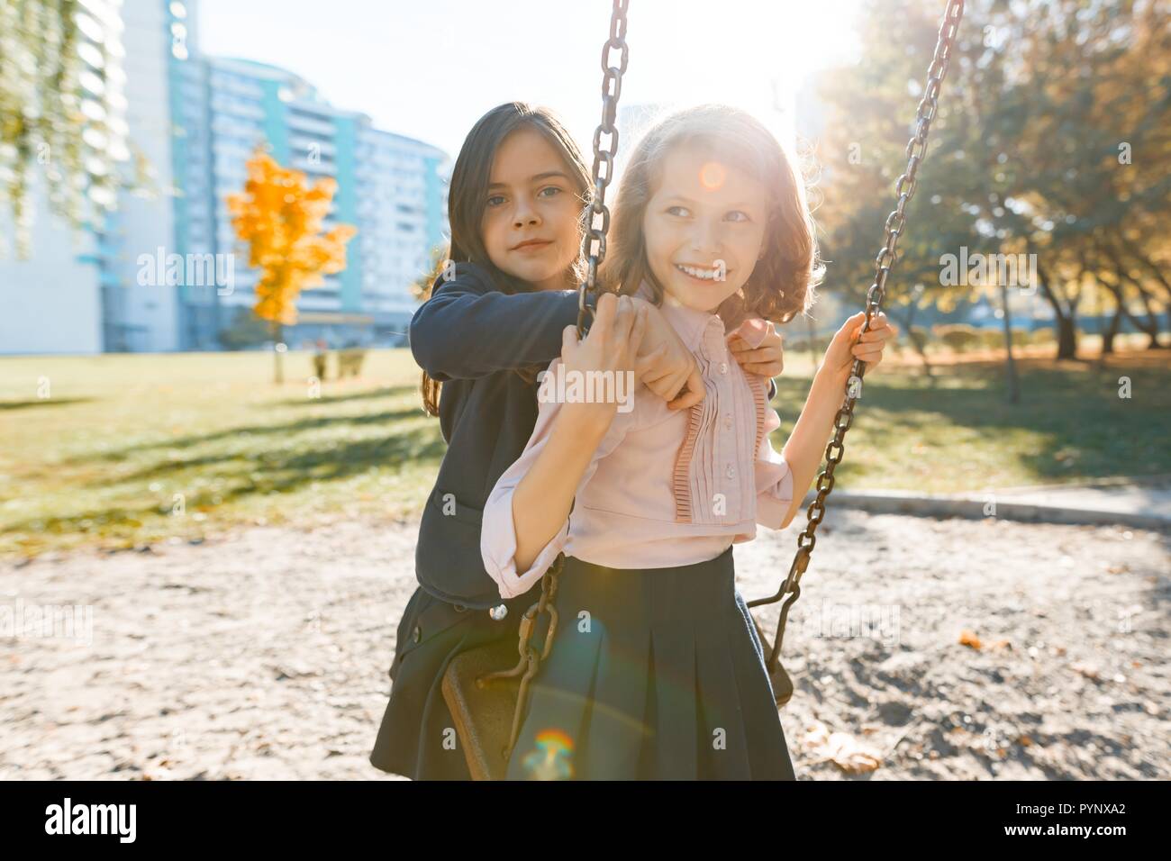 Portrait of two girls children hugging and swinging in a sunny autumn ...