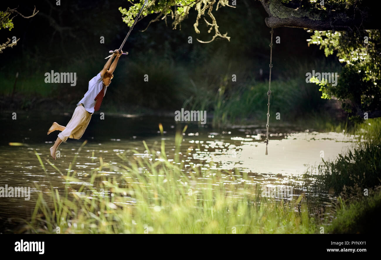 A boy swinging over a pond Stock Photo - Alamy