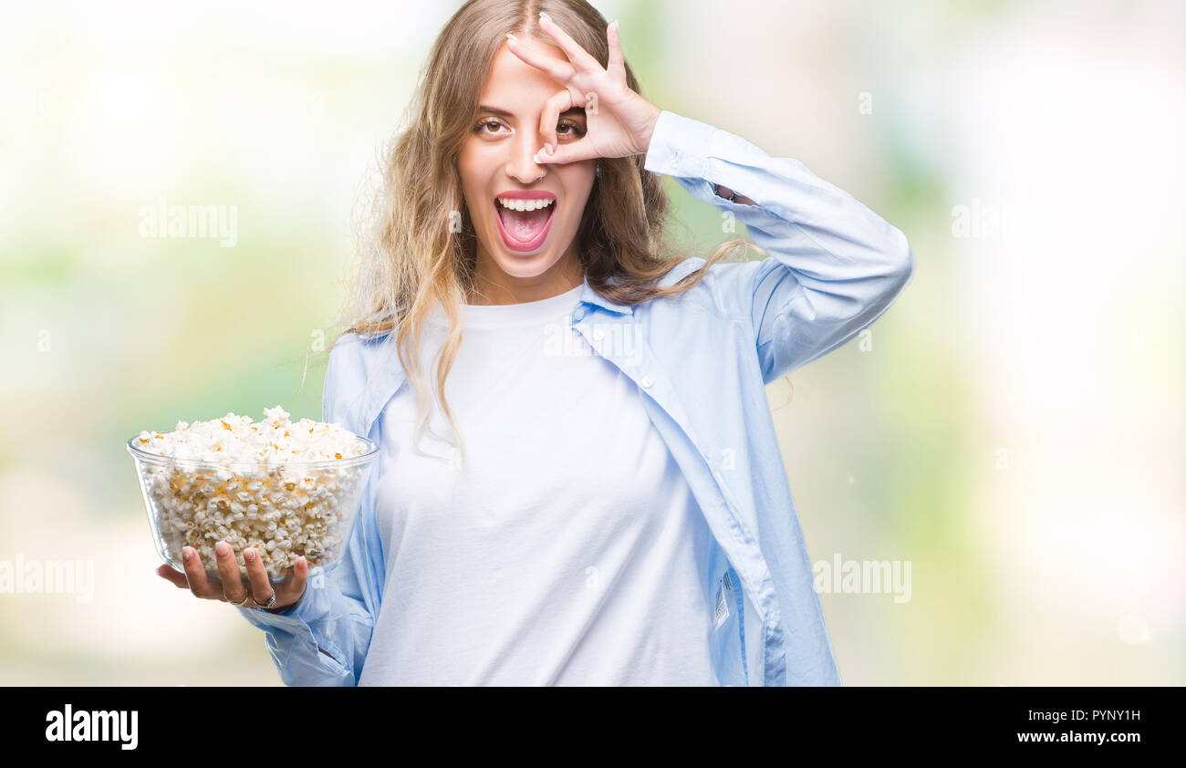 Beautiful young blonde woman eating popcorn over isolated background ...