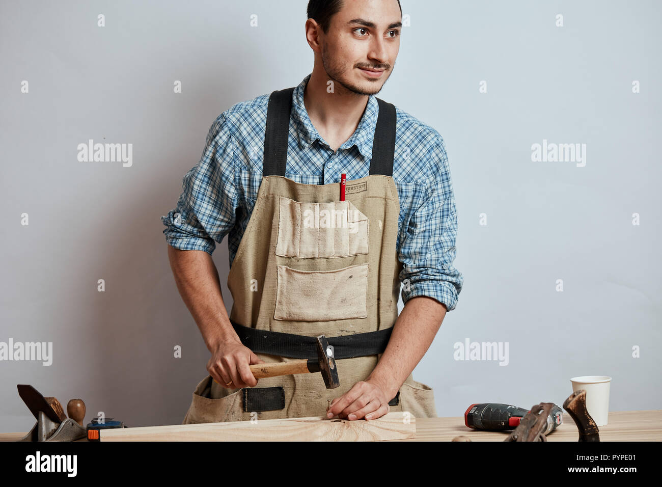 The carpenter hammering down a nail to wooden plank, making a furniture ...