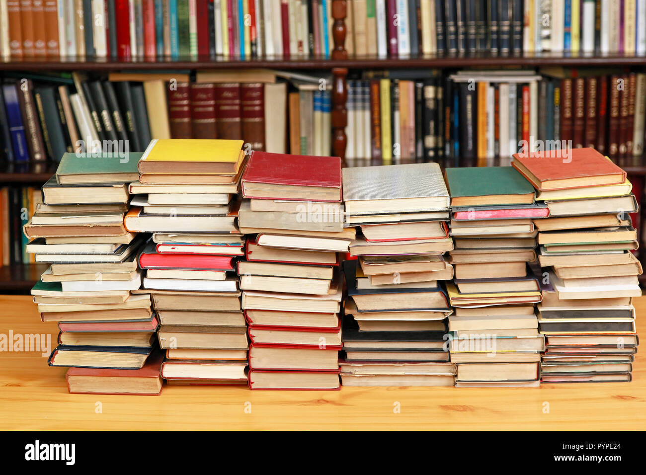 Large pile of old books with library shelves in the background Stock ...