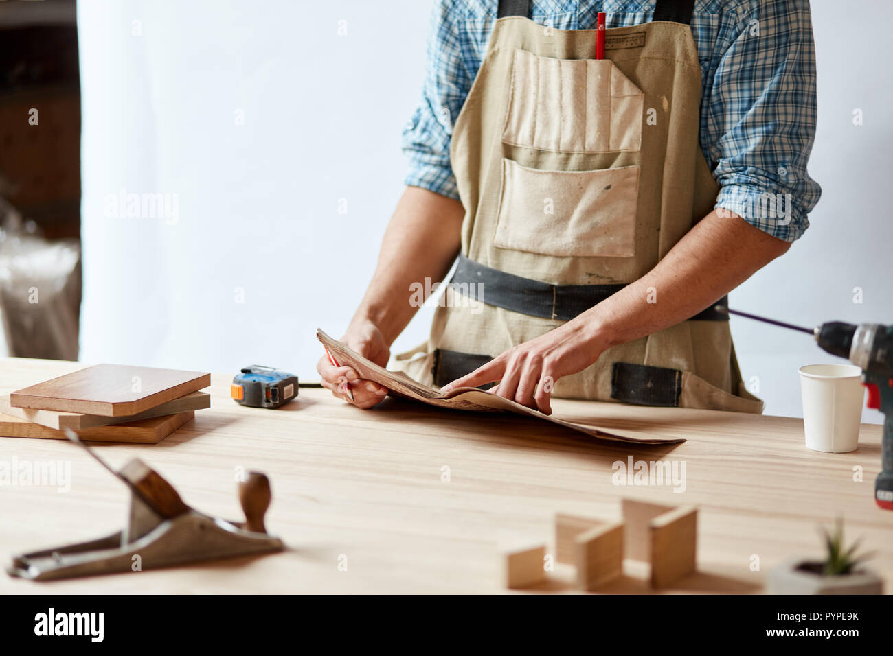 Closeup view of a carpenter using a red pencil to draw a line on a ...