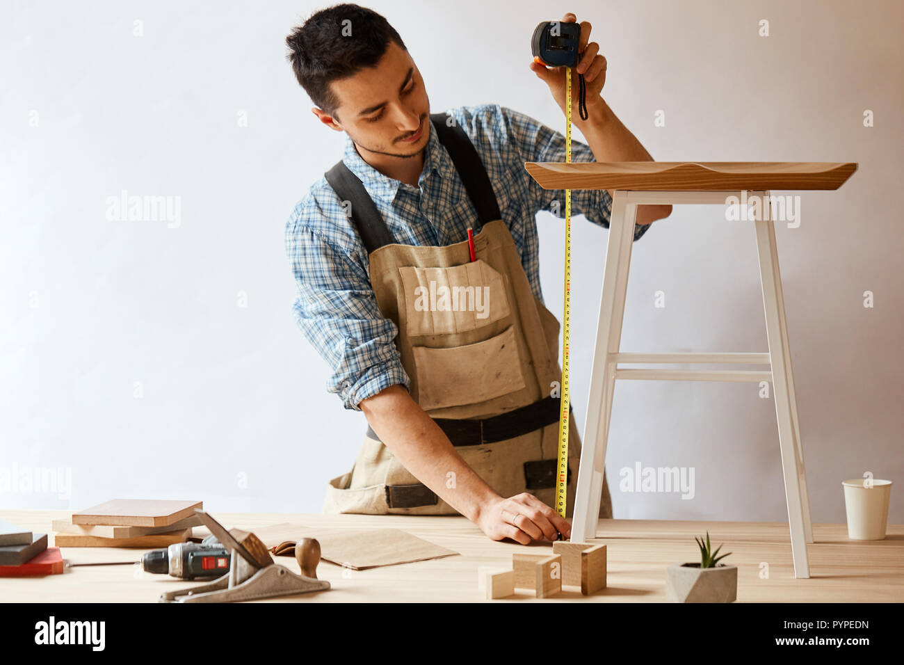 Young man measuring home furniture with measure tape. Repair concept ...