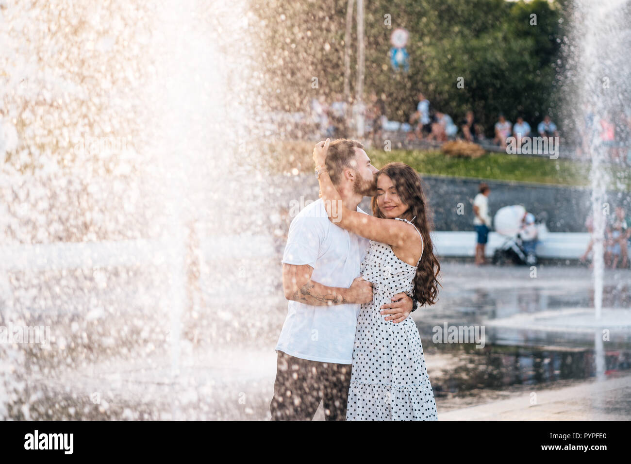 Handsome guy kisses the beautiful girl on a background of a fountain ...