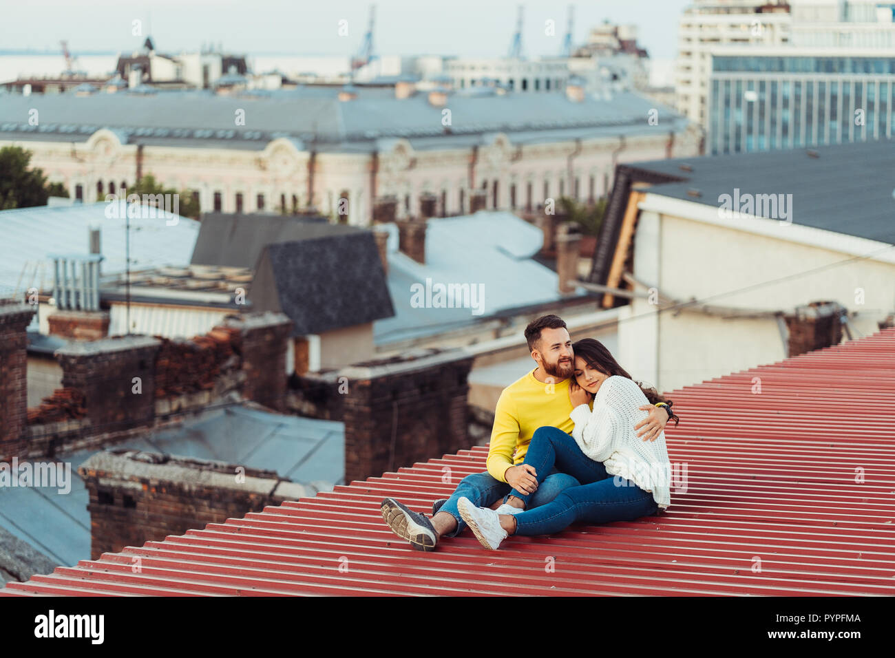 Loving young couple is sitting on the roof of the house Stock Photo - Alamy