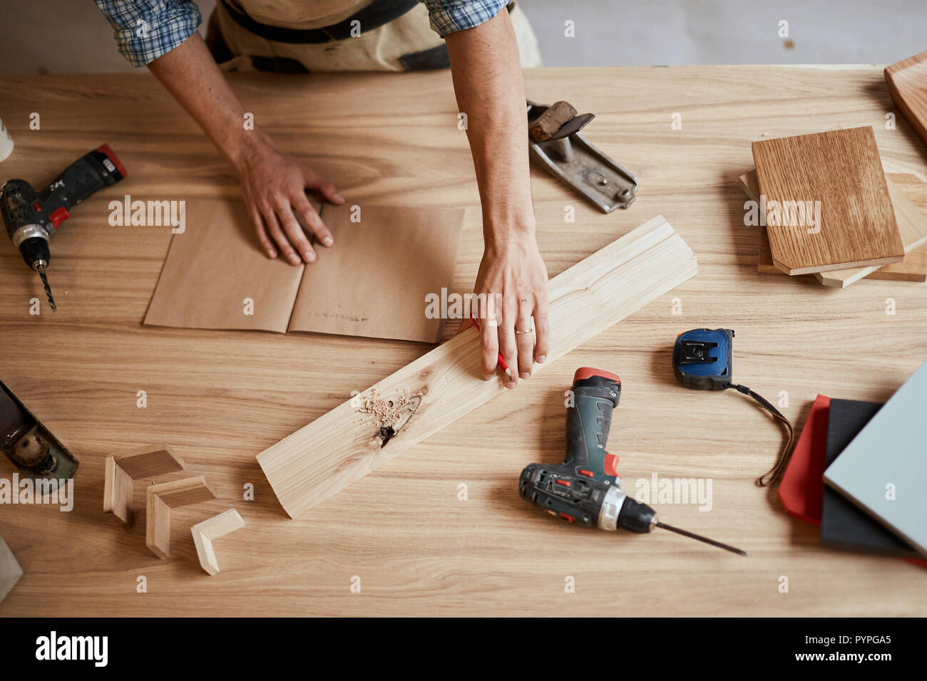 Closeup view of a carpenter using a red pencil to draw a line on a ...