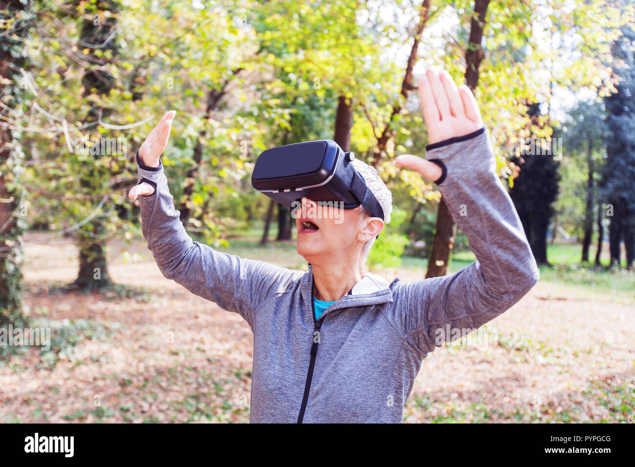 Surprised Senior woman fun with virtual reality headset in forest, VR ...