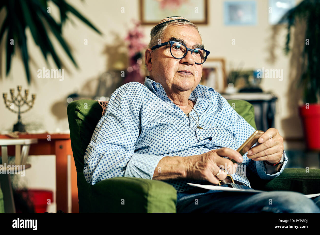 Jewish senior with glasses sitting in the armchair reading a torah book ...