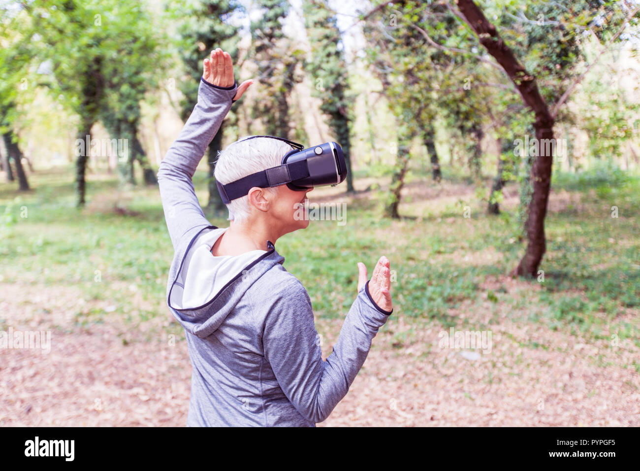 Senior woman fun with virtual reality headset in forest, VR device ...