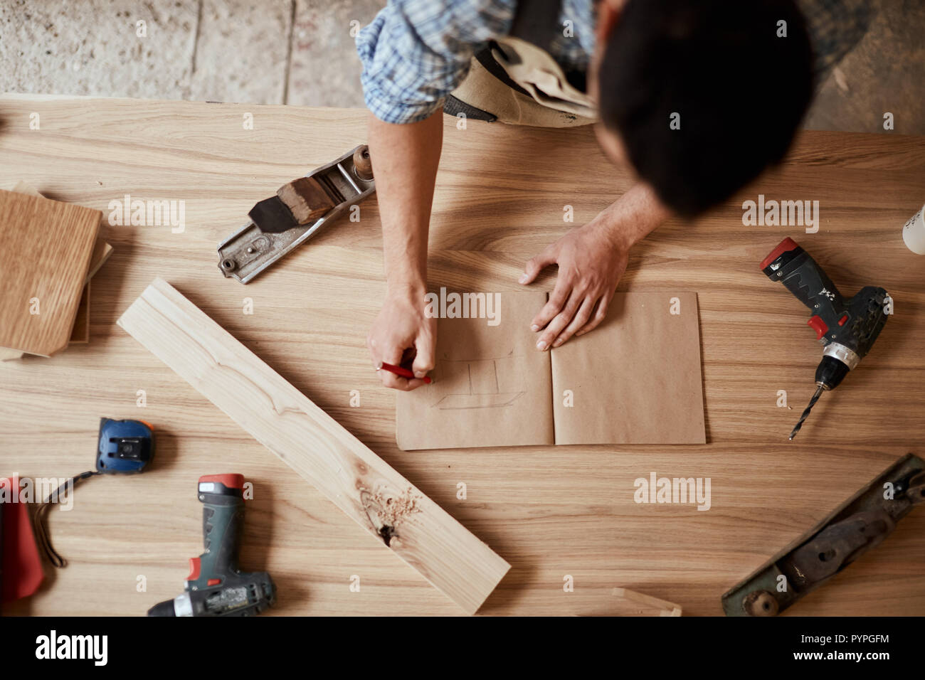 Closeup view of a carpenter using a red pencil to draw a line on a ...