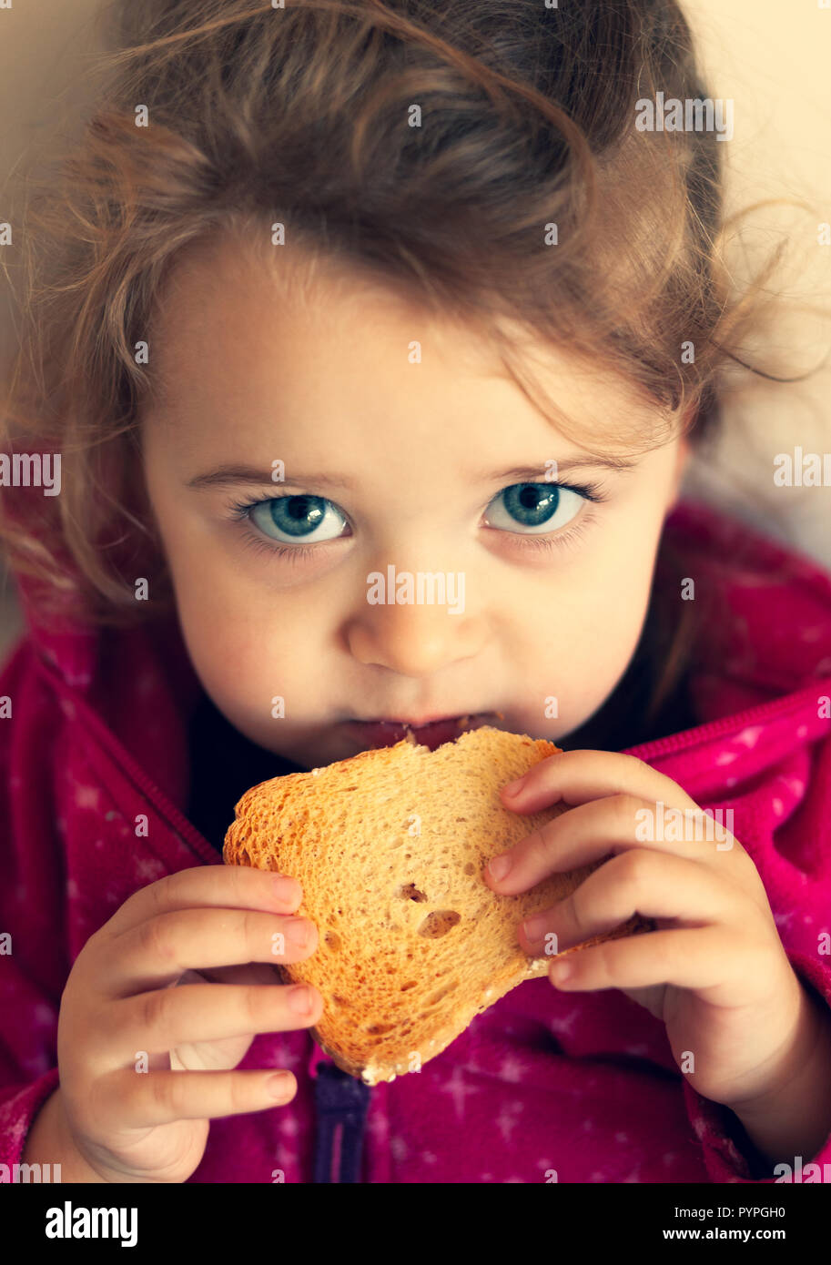 Portrait of a little girl eating a rusk Stock Photo - Alamy