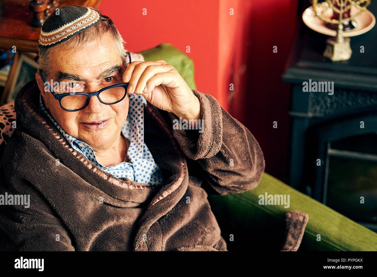 Jewish senior with glasses sitting in the green armchair Stock Photo ...