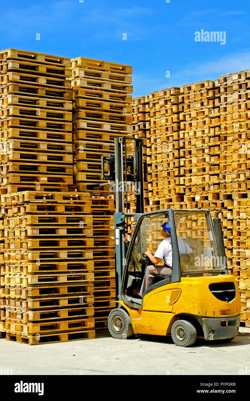 Forklift operator lifting bunch of wooden pallets Stock Photo - Alamy