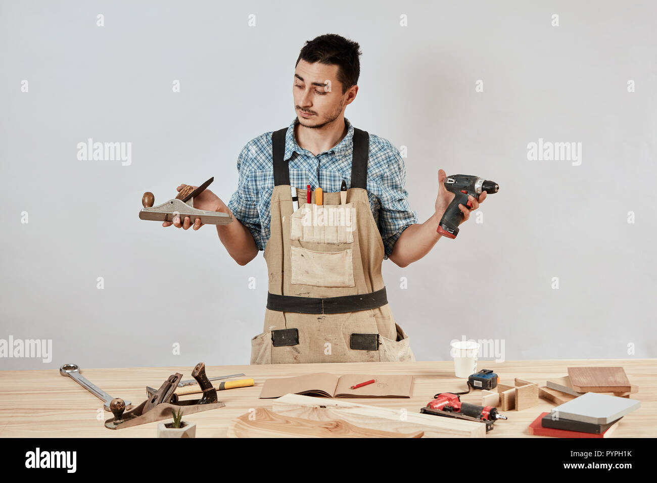 Emotional male carpenter in workwear and apron having confused puzzled ...