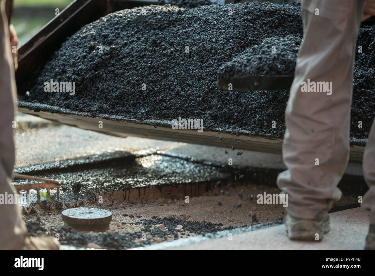 Construction workers applying gravel and cement to a bump in the road ...