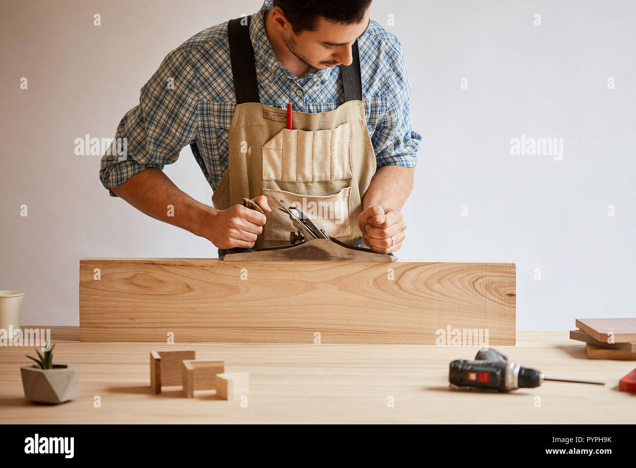 carpenter working with wood using plane against white wall in studio ...