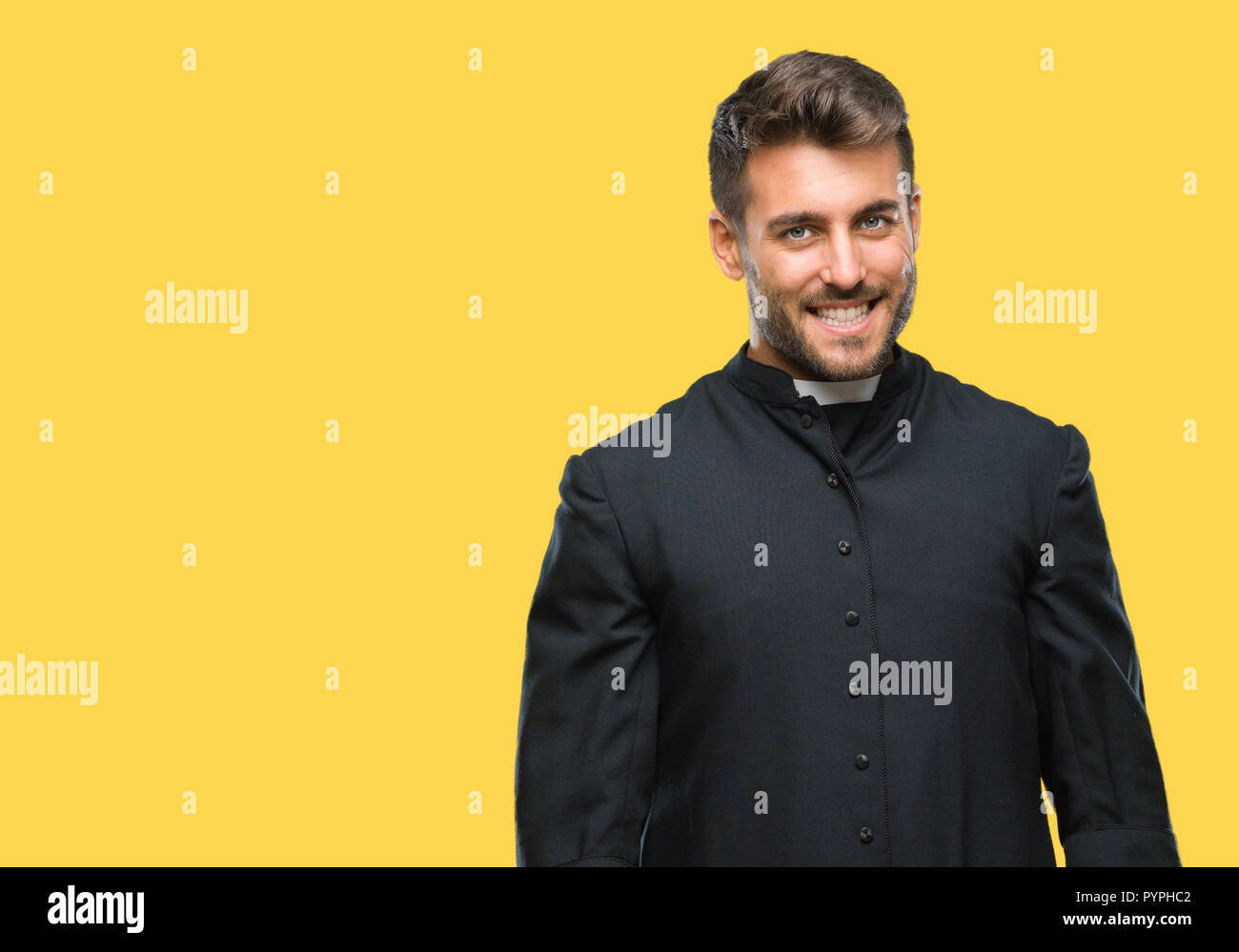 Young catholic christian priest man over isolated background looking ...