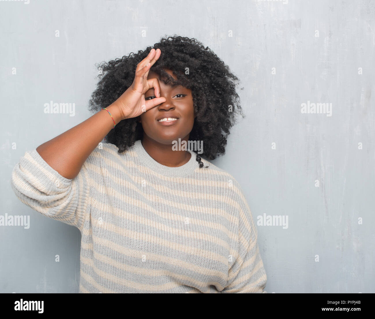 Young african american plus size woman over grey grunge wall wearing a ...