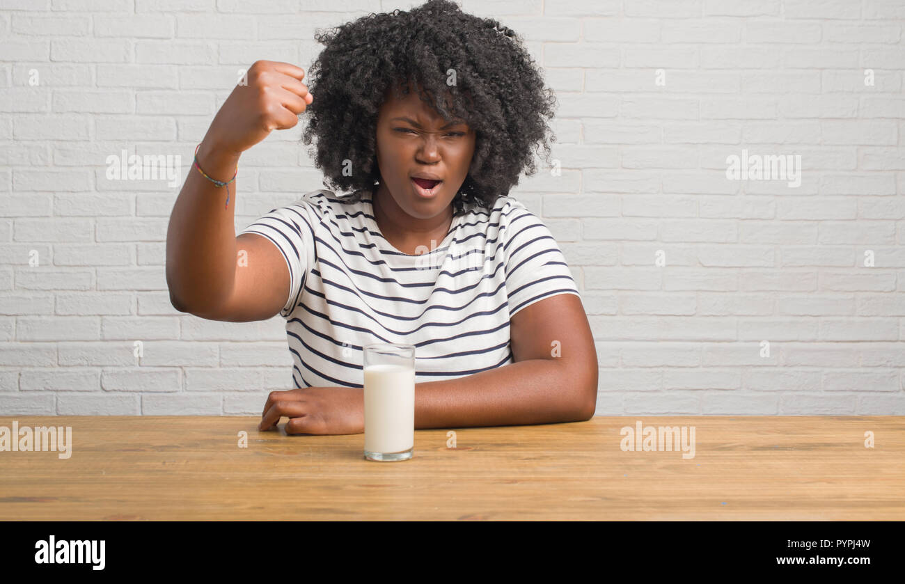 Young african american woman sitting on the table drinking a glass of ...