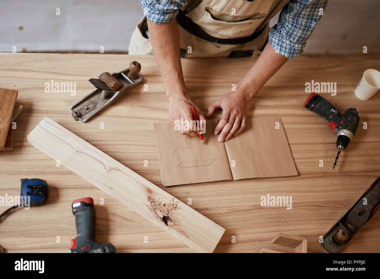 Closeup view of a carpenter using a red pencil to draw a line on a ...