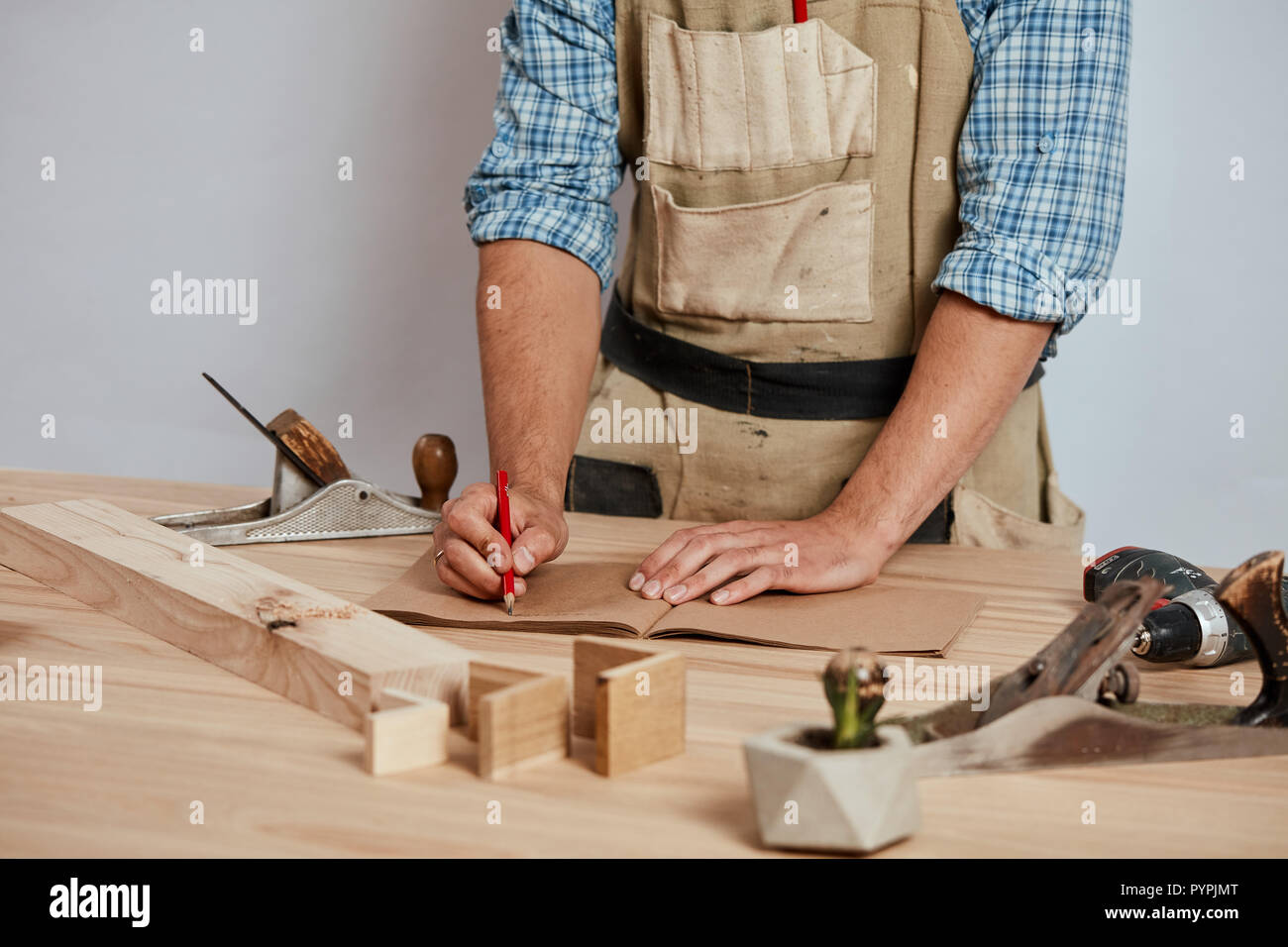 Closeup view of a carpenter using a red pencil to draw a line on a ...