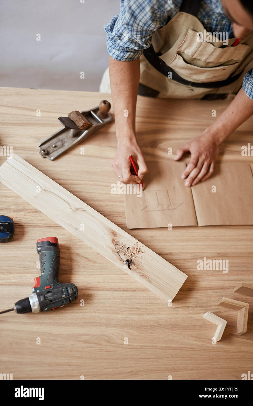Closeup view of a carpenter using a red pencil to draw a line on a ...