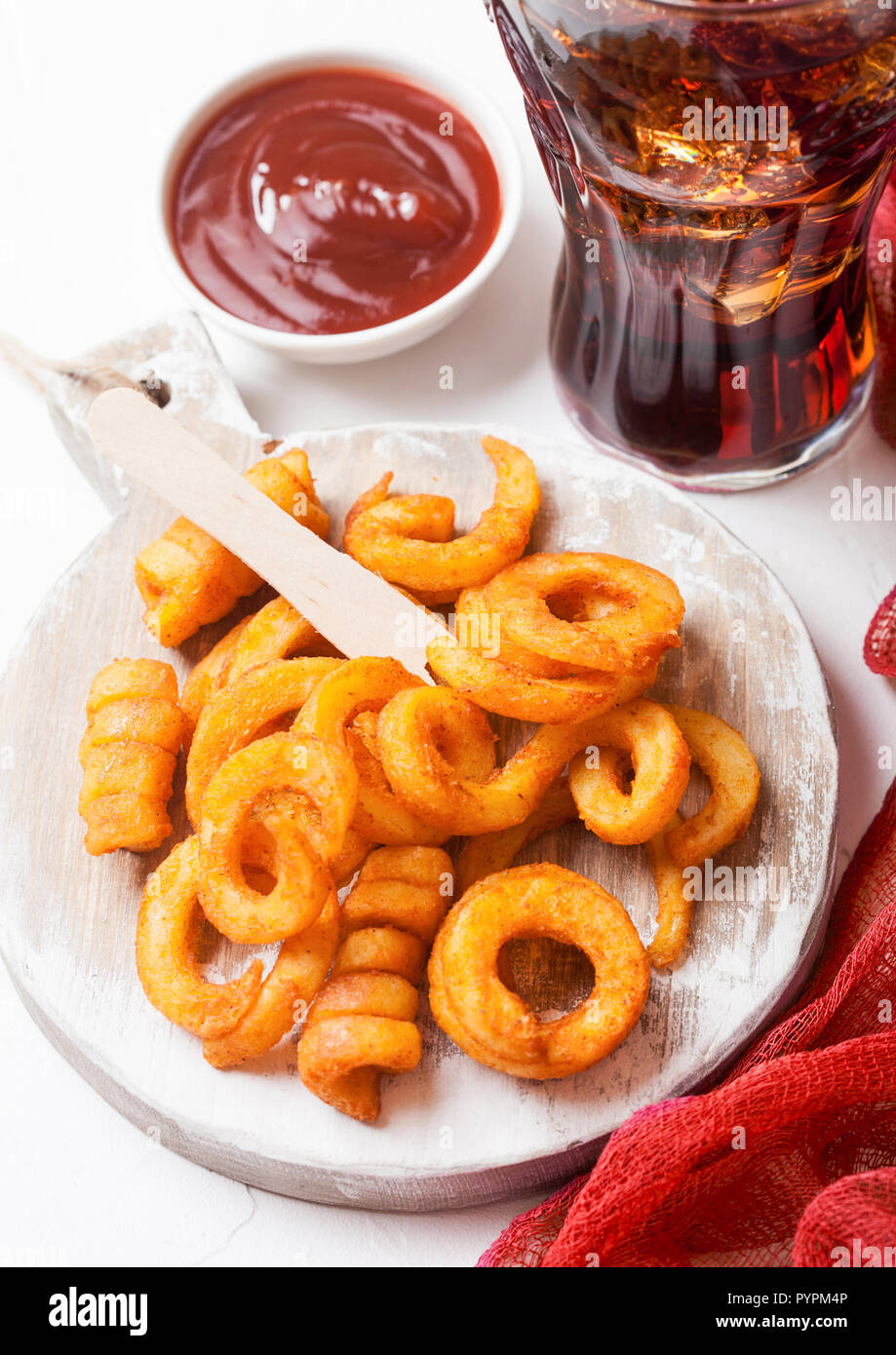 Curly fries fast food snack on wooden board with ketchup and glass of ...