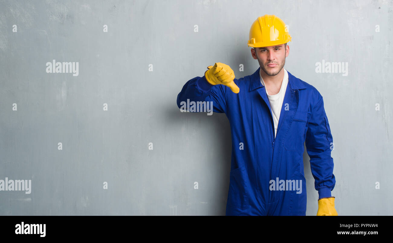 Young caucasian man over grey grunge wall wearing contractor uniform ...