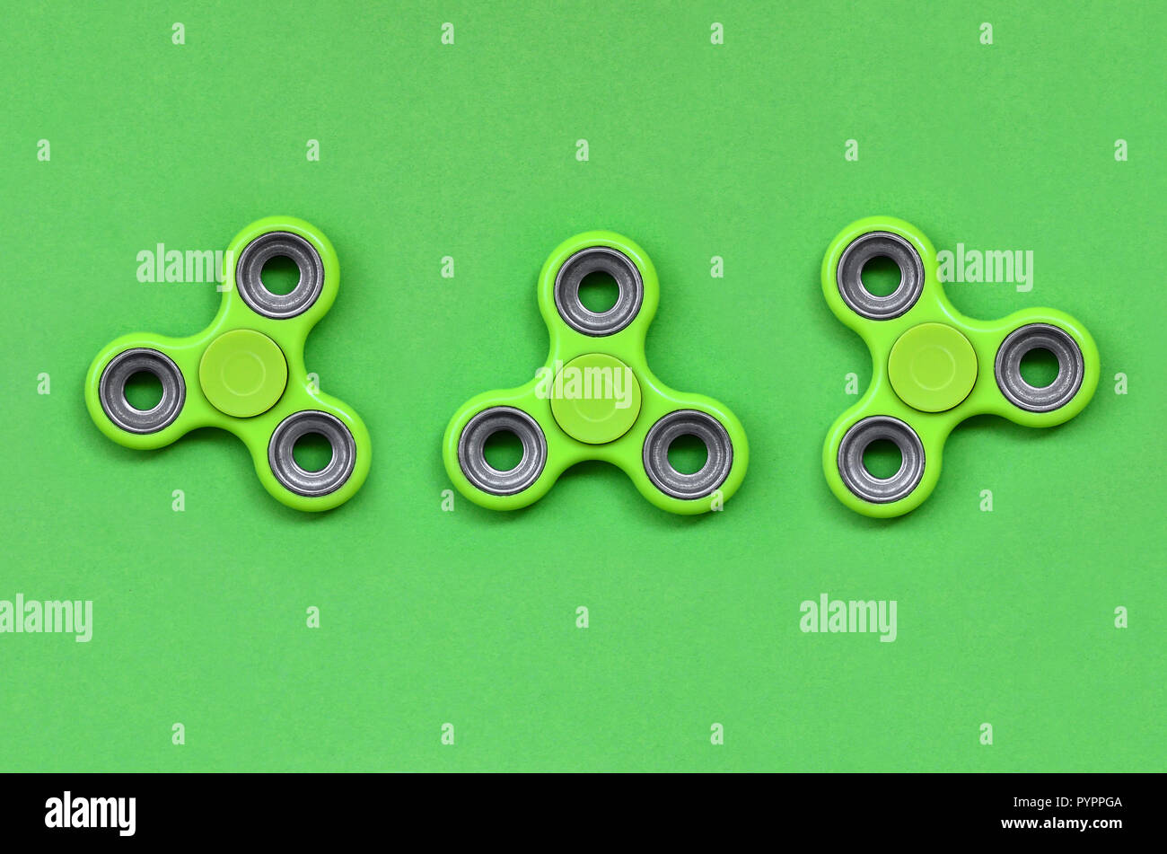 Many green fidget spinners lies on texture background of fashion pastel ...